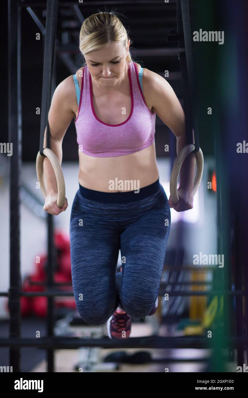 young athlete woman working out pull ups with gymnastic rings at the ...