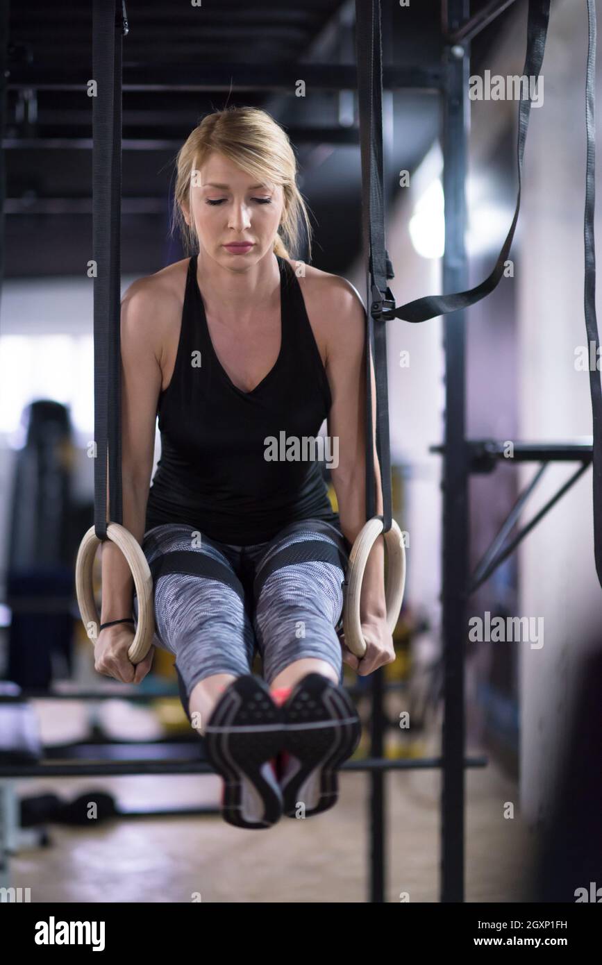 young athlete woman working out pull ups with gymnastic rings at the ...