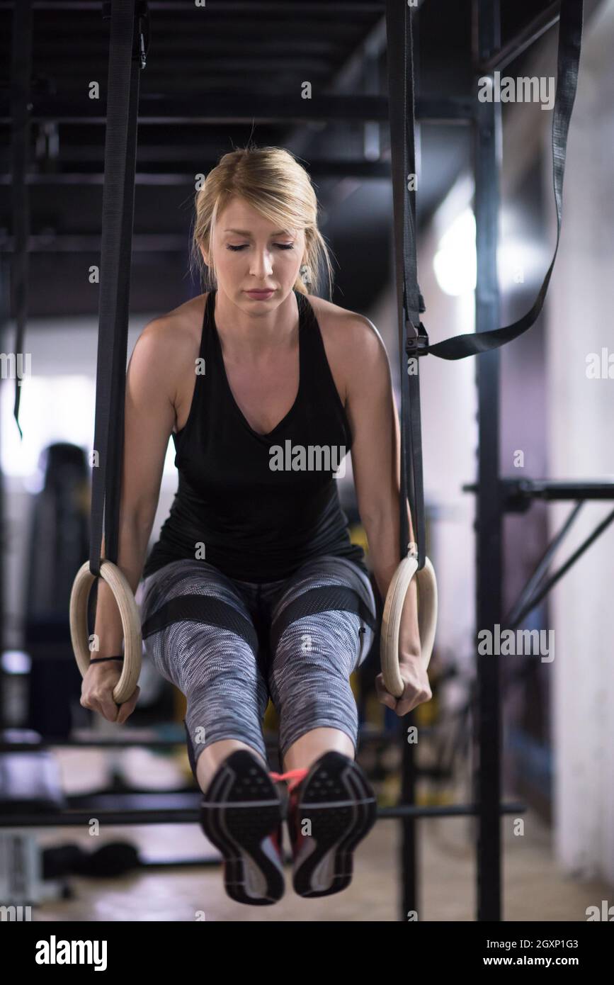 young athlete woman working out pull ups with gymnastic rings at the ...