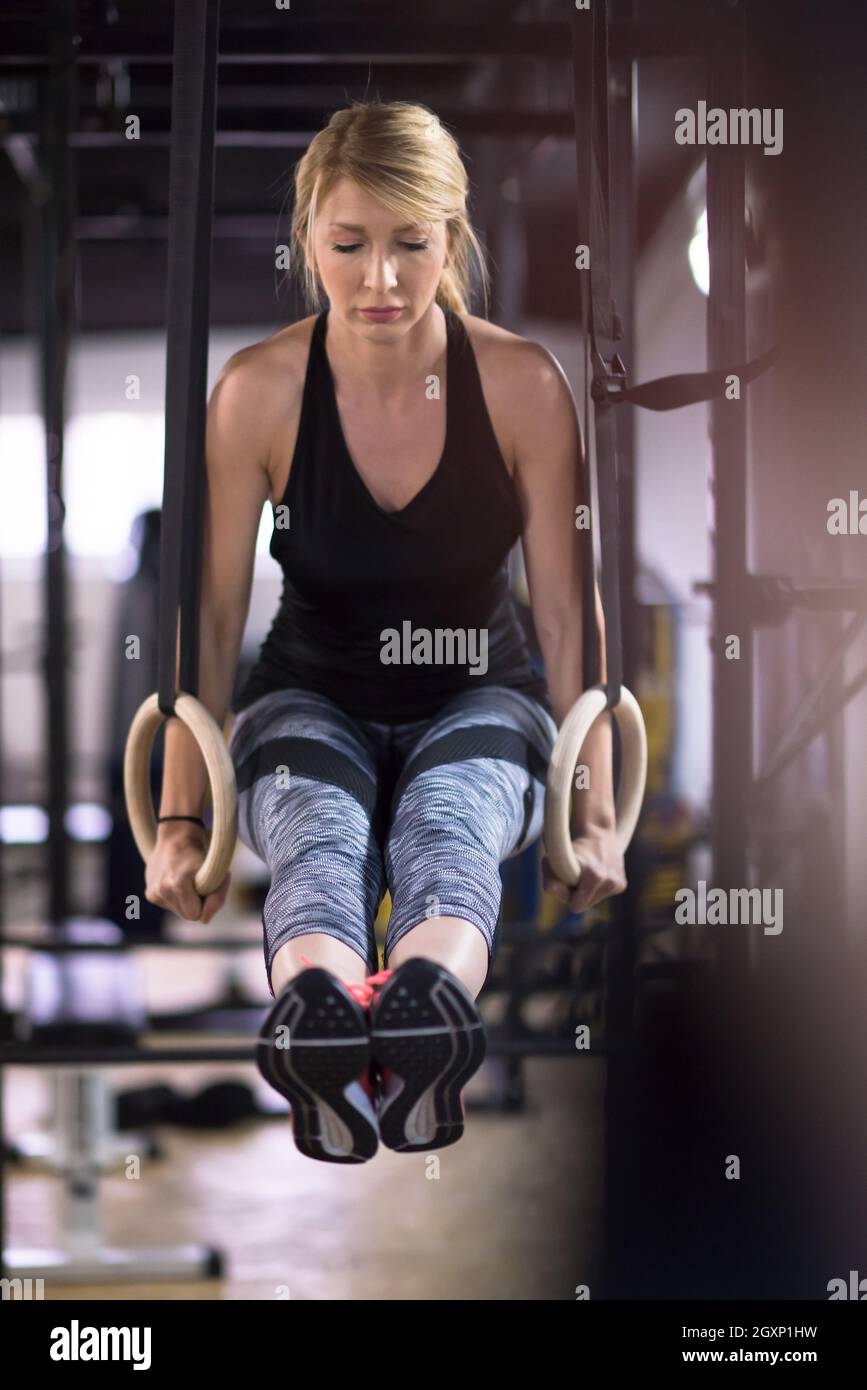 young athlete woman working out pull ups with gymnastic rings at the ...
