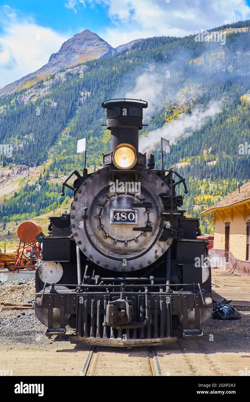 Vertical close-up front of locomotive train with wall of mountains in ...