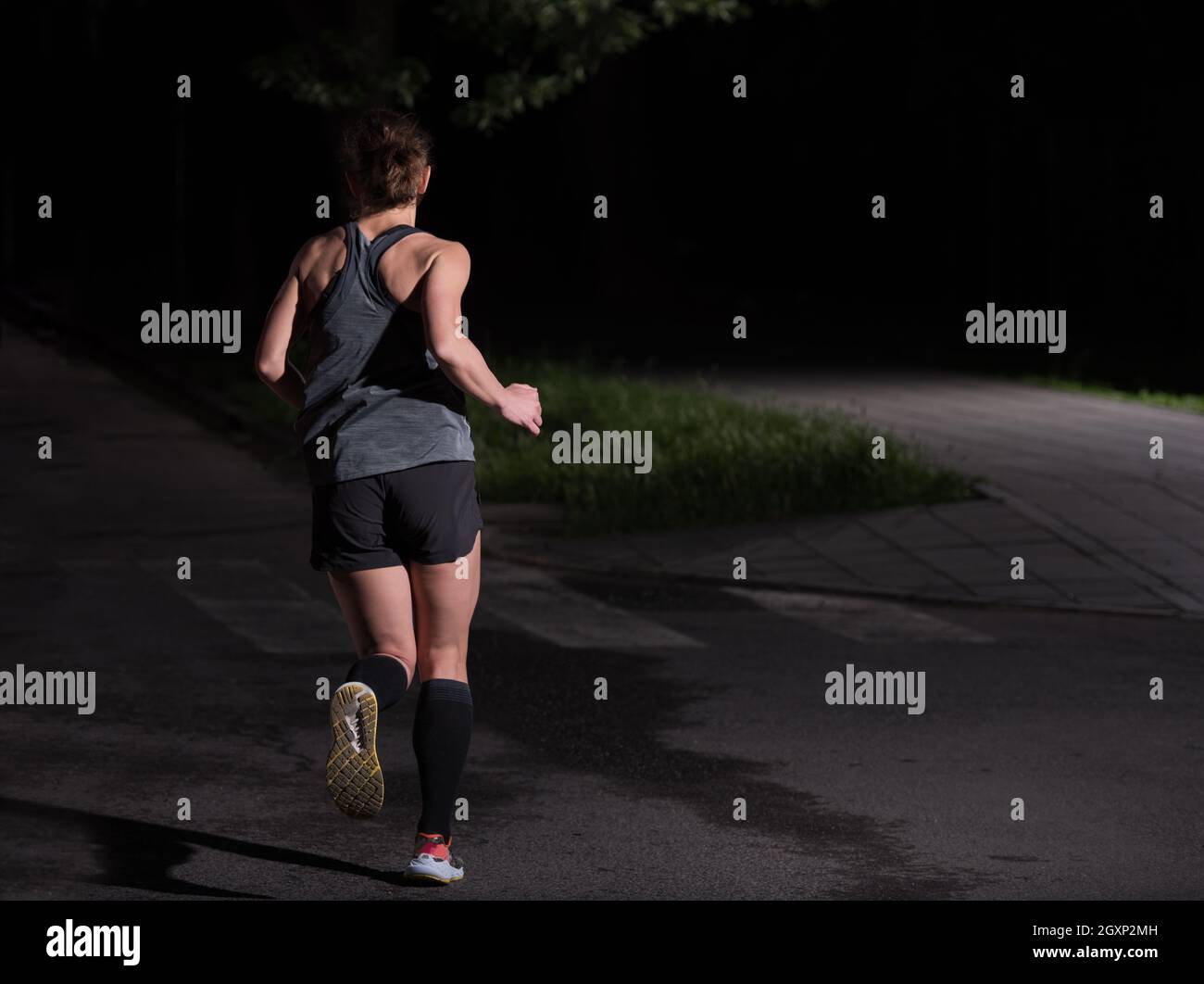 fit muscular female runner training for marathon running at night on ...