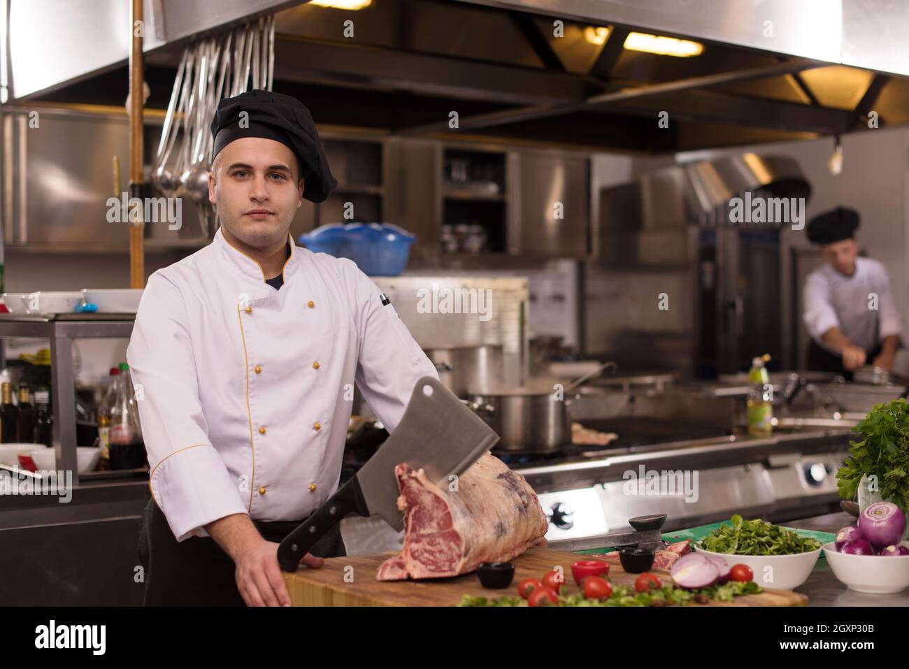 chef using ax while cutting big piece of beef on wooden board in ...