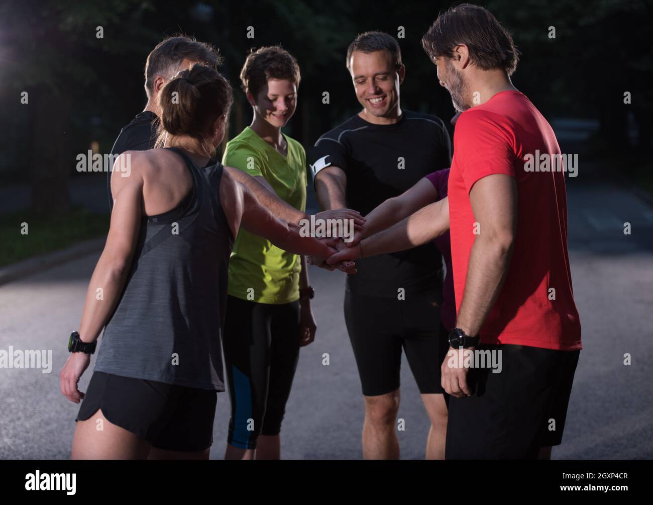 Group of healthy runners giving high five to each other while ...