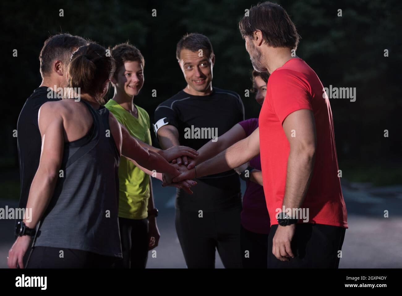 Group of healthy runners giving high five to each other while ...