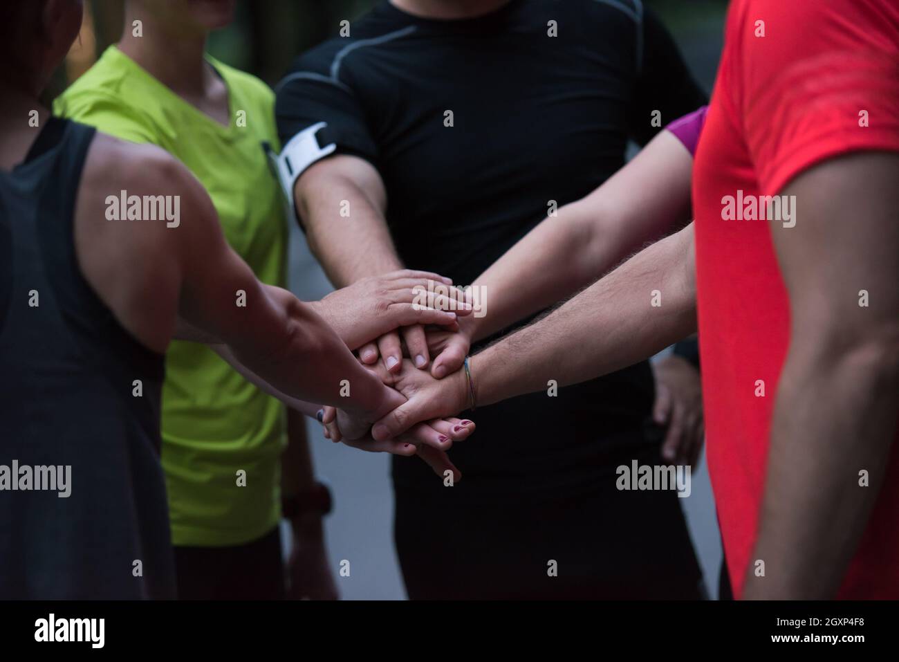 Group of healthy runners giving high five to each other while ...