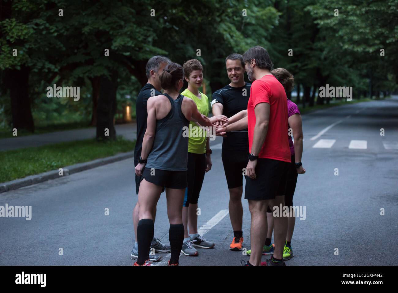 Group of healthy runners giving high five to each other while ...