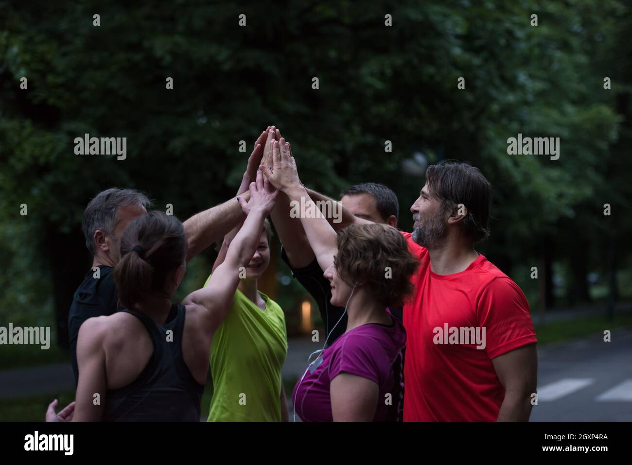 Group of healthy runners giving high five to each other while ...