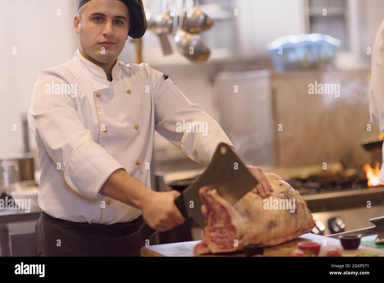 chef using ax while cutting big piece of beef on wooden board in ...