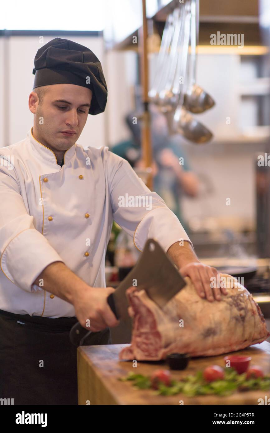 chef using ax while cutting big piece of beef on wooden board in ...