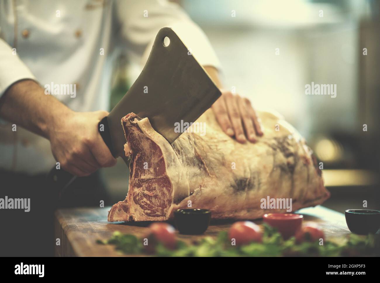 chef using ax while cutting big piece of beef on wooden board in ...