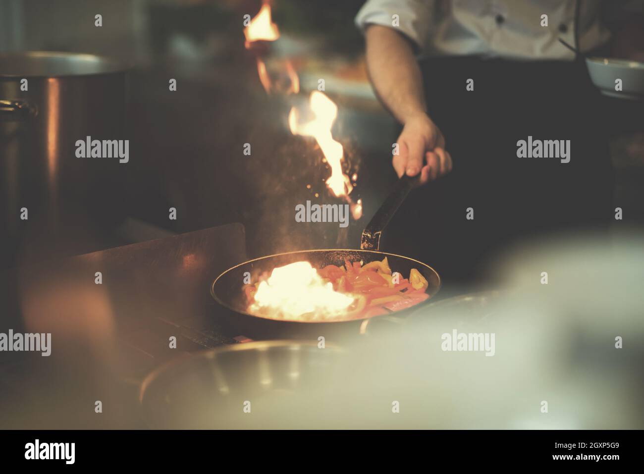 Chef cooking and doing flambe on food in restaurant kitchen Stock Photo ...