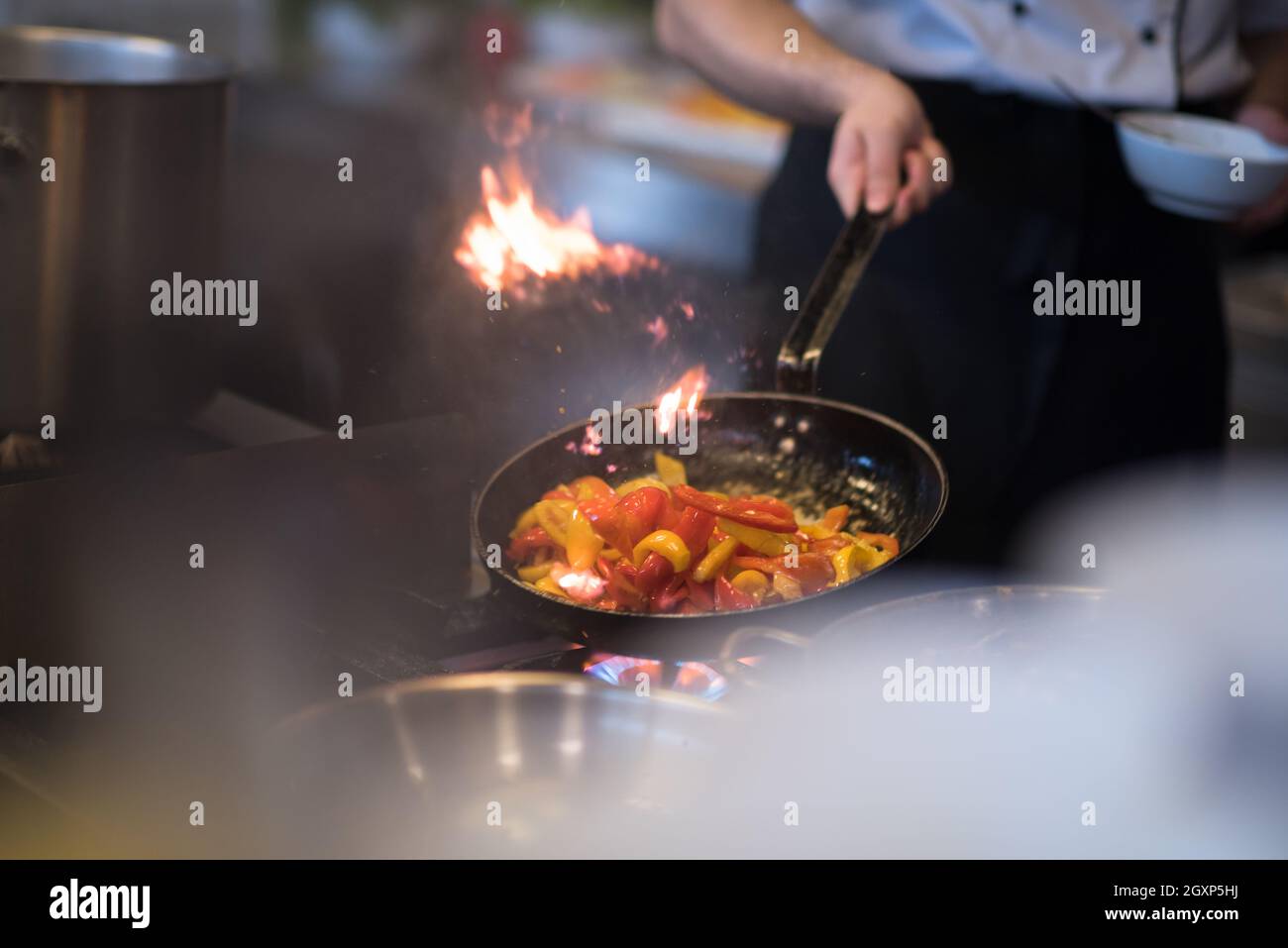 Chef cooking and doing flambe on food in restaurant kitchen Stock Photo ...