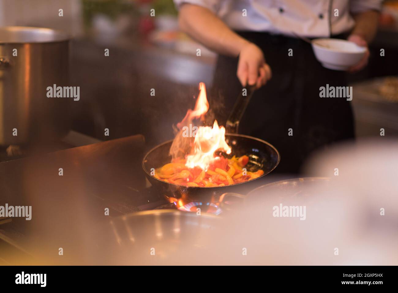 Chef cooking and doing flambe on food in restaurant kitchen Stock Photo ...