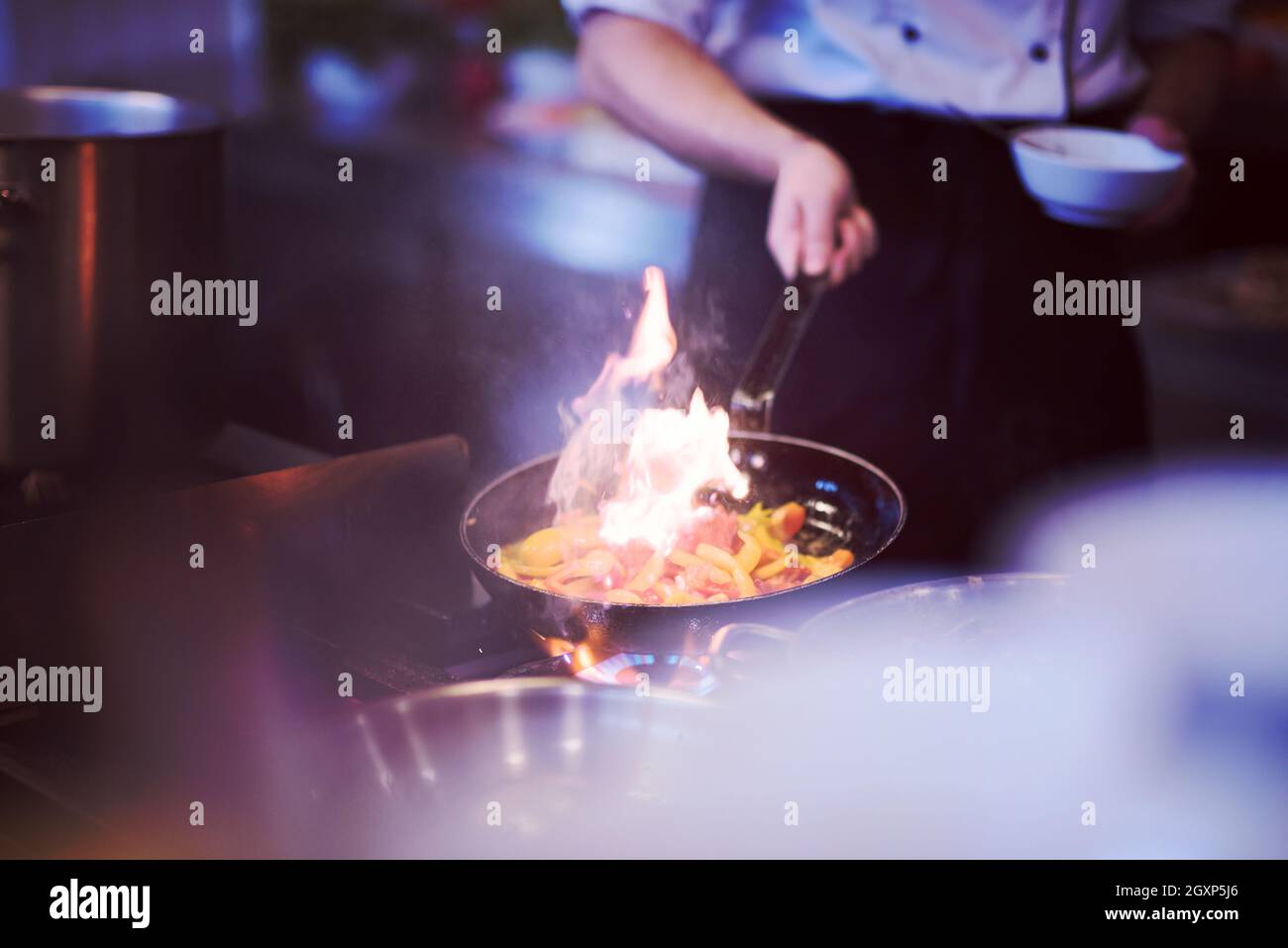 Chef cooking and doing flambe on food in restaurant kitchen Stock Photo ...