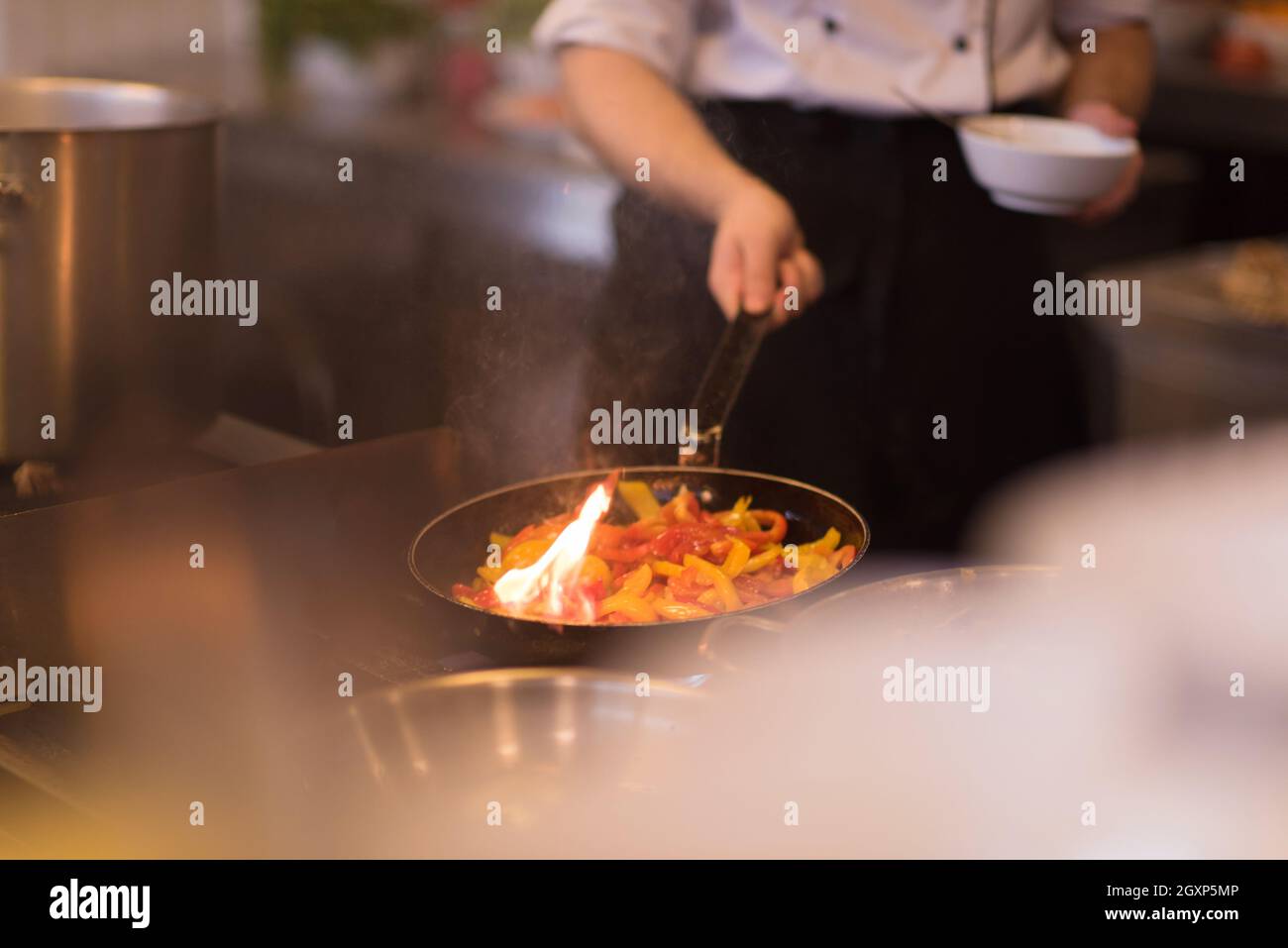 Chef cooking and doing flambe on food in restaurant kitchen Stock Photo ...