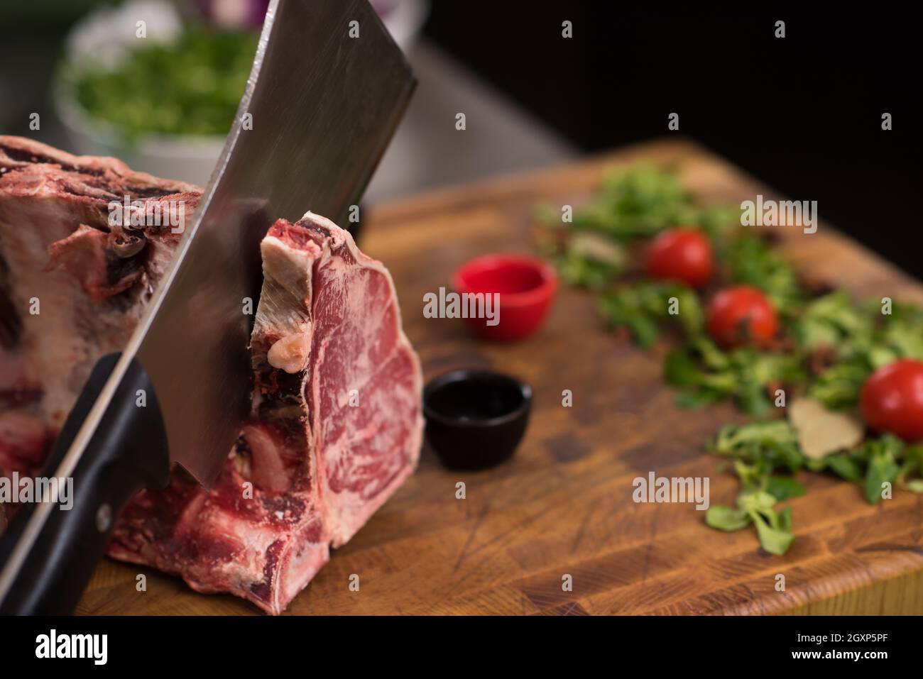 chef using ax while cutting big piece of beef on wooden board in ...