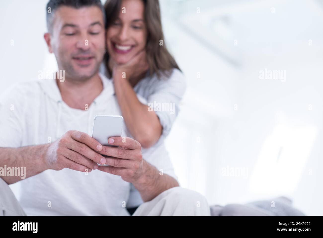 Young happy couple using mobile phone at home together, looking at ...