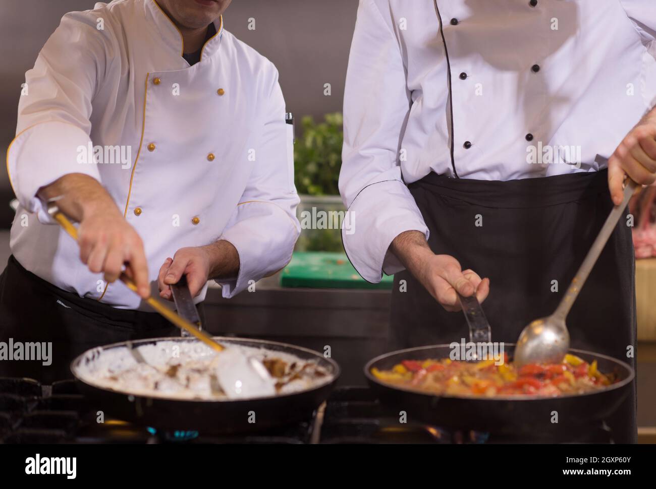 Professional team cooks and chefs preparing meal at busy hotel or ...