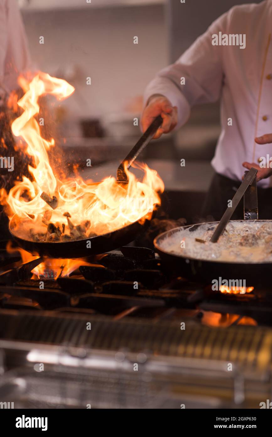 Chef cooking and doing flambe on food in restaurant kitchen Stock Photo ...
