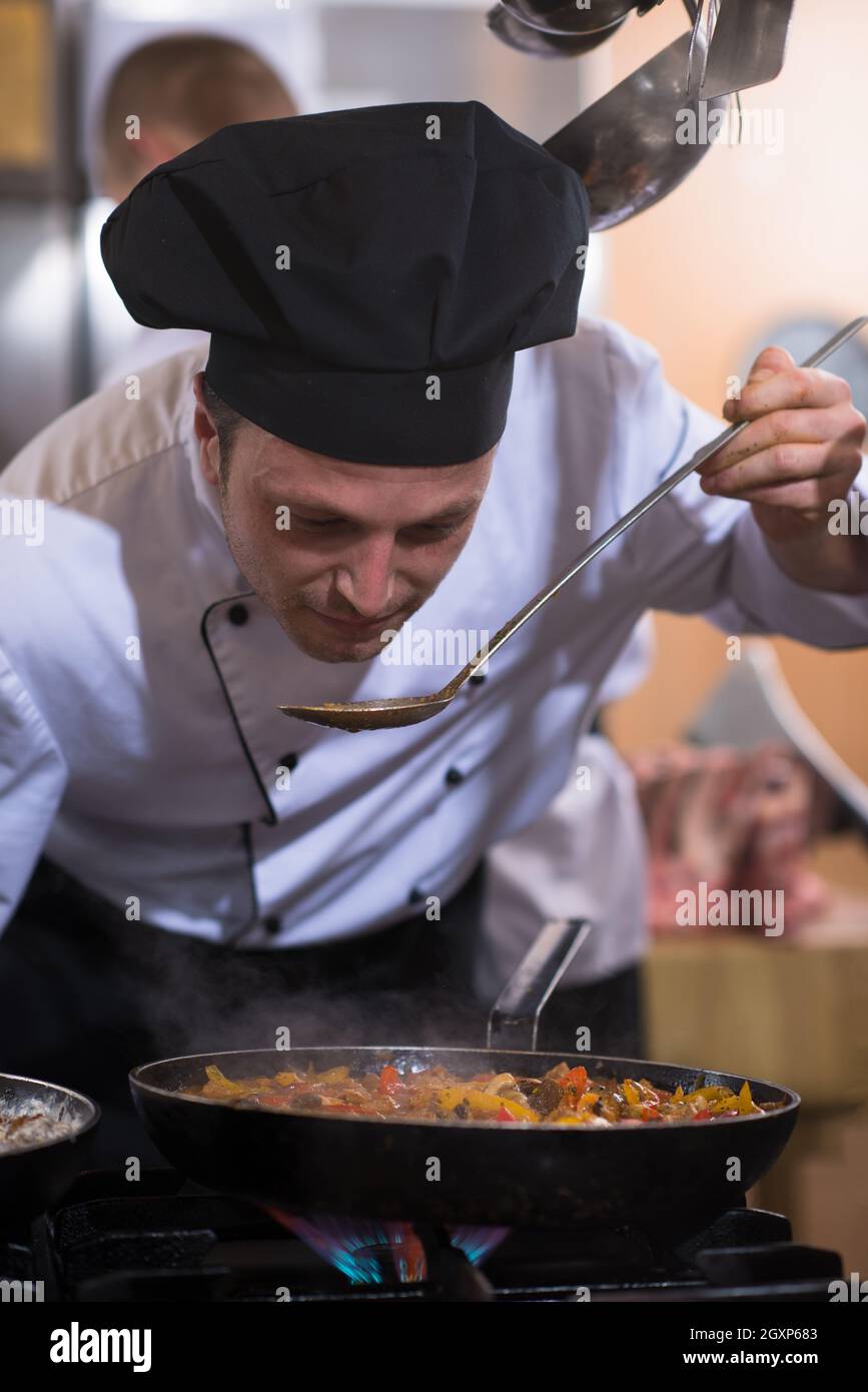 Handsome chef tasting food with spoon at the restaurant kitchen Stock ...