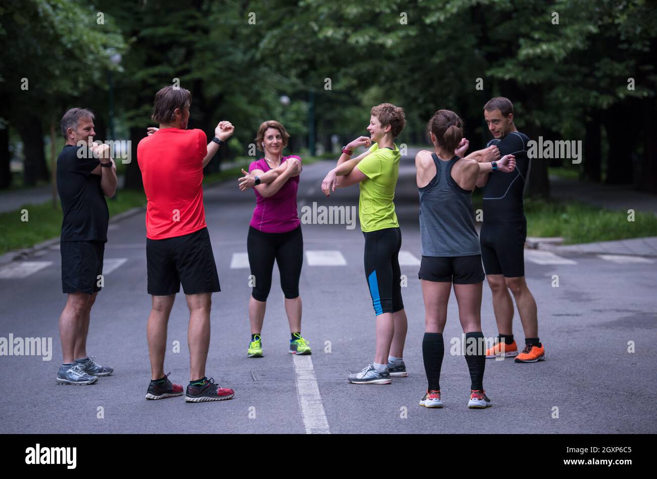 healthy runners team warming up and stretching in city park before ...