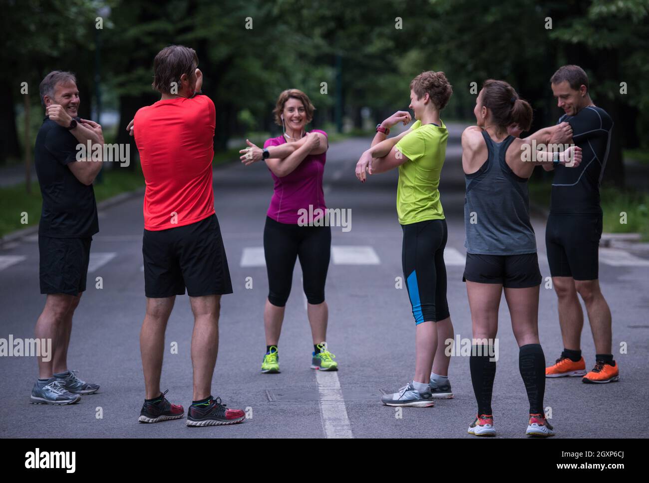 healthy runners team warming up and stretching in city park before ...