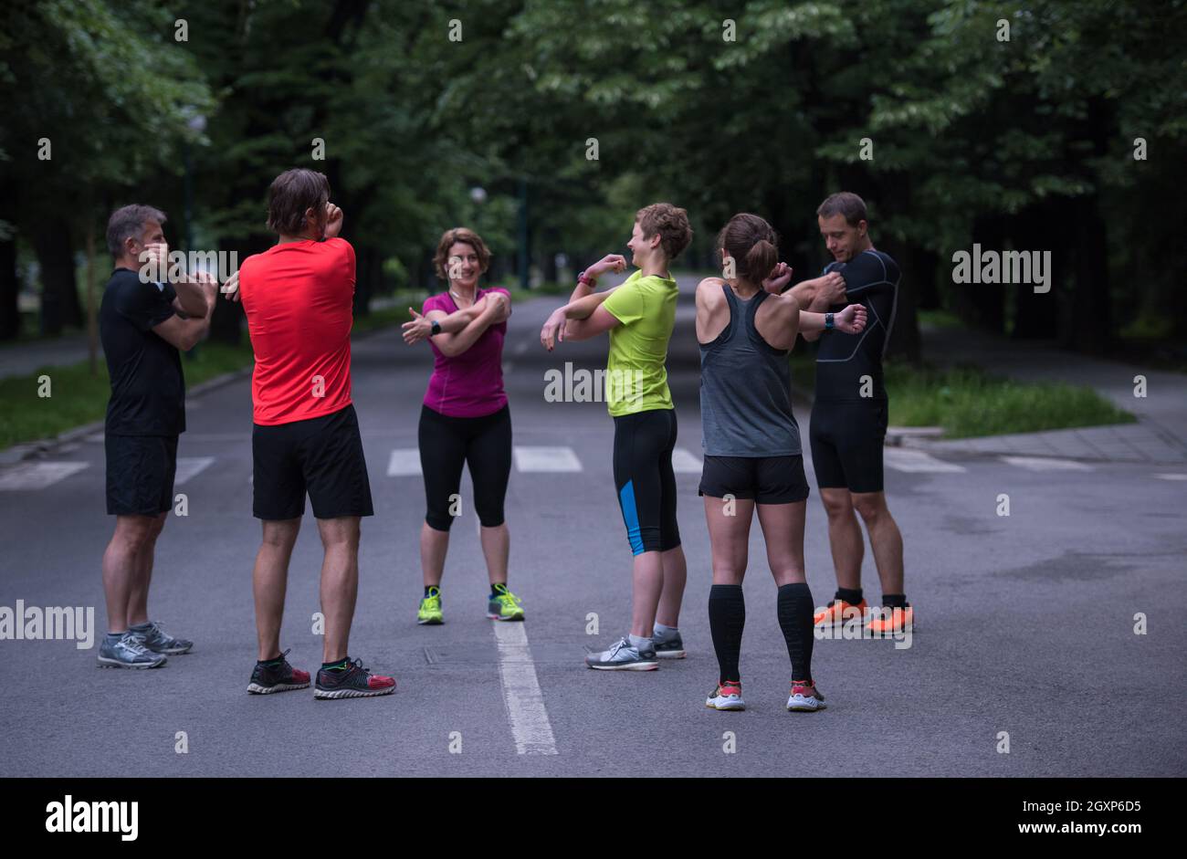 healthy runners team warming up and stretching in city park before ...