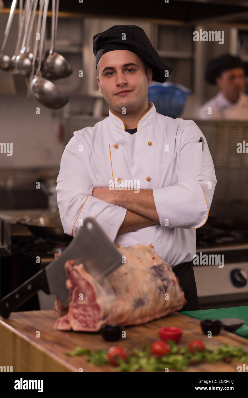 chef using ax while cutting big piece of beef on wooden board in ...