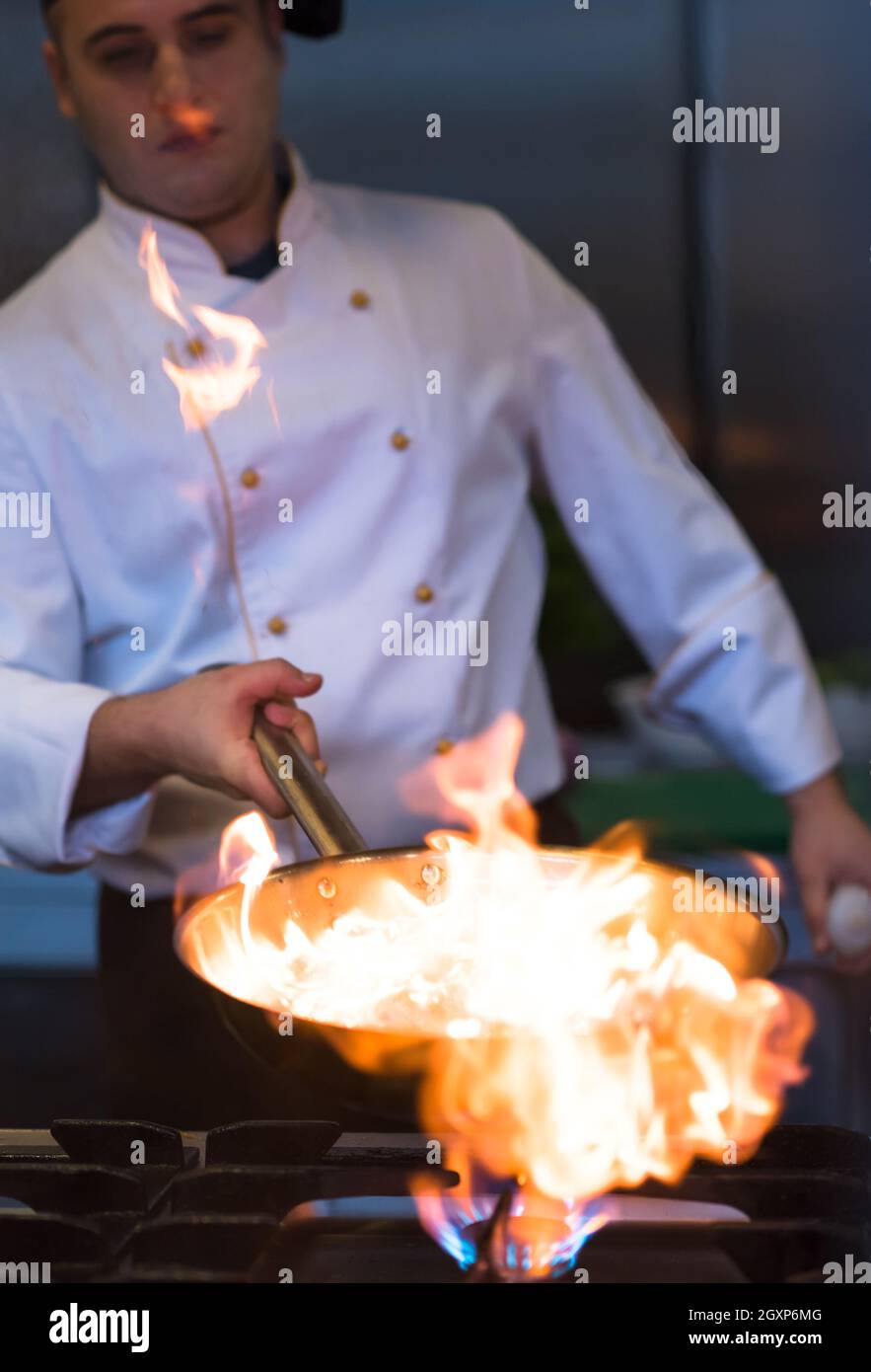 Chef cooking and doing flambe on food in restaurant kitchen Stock Photo ...