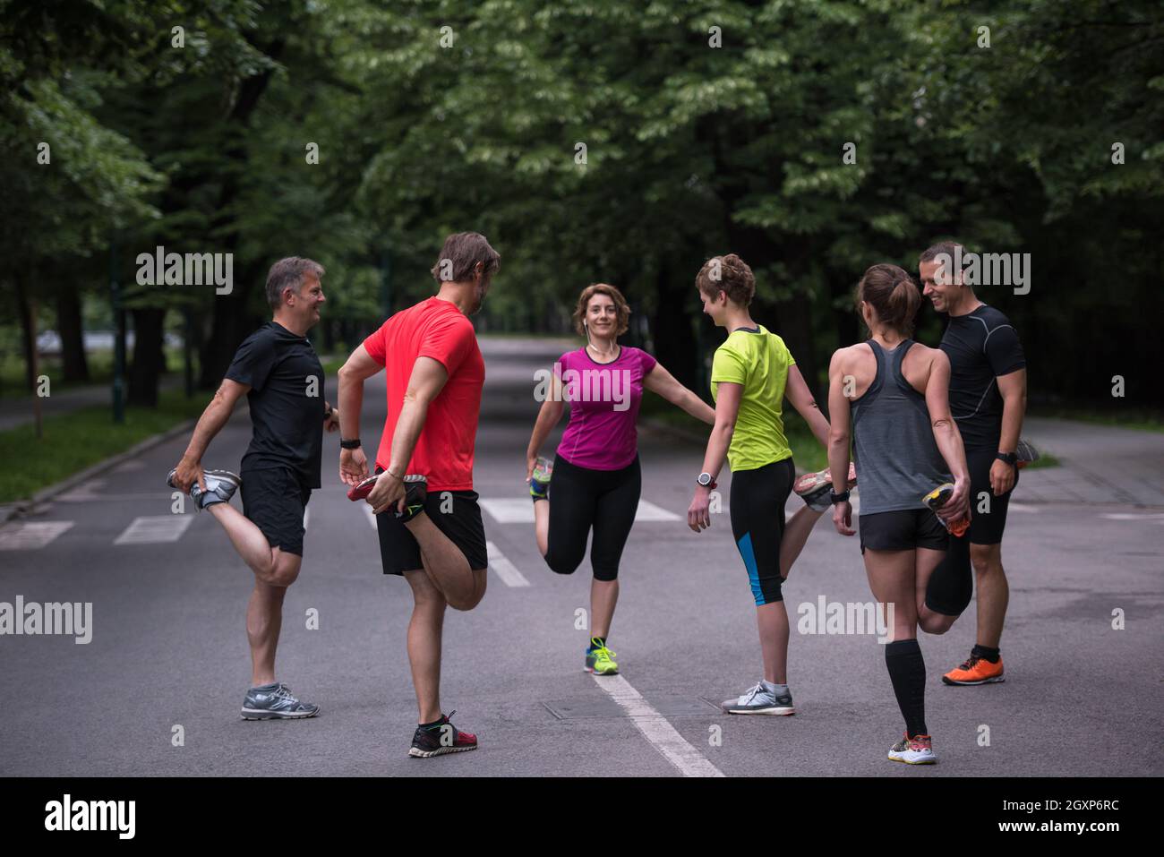 healthy runners team warming up and stretching in city park before ...