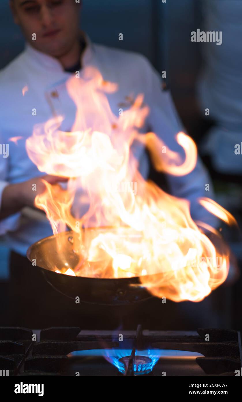Chef cooking and doing flambe on food in restaurant kitchen Stock Photo ...