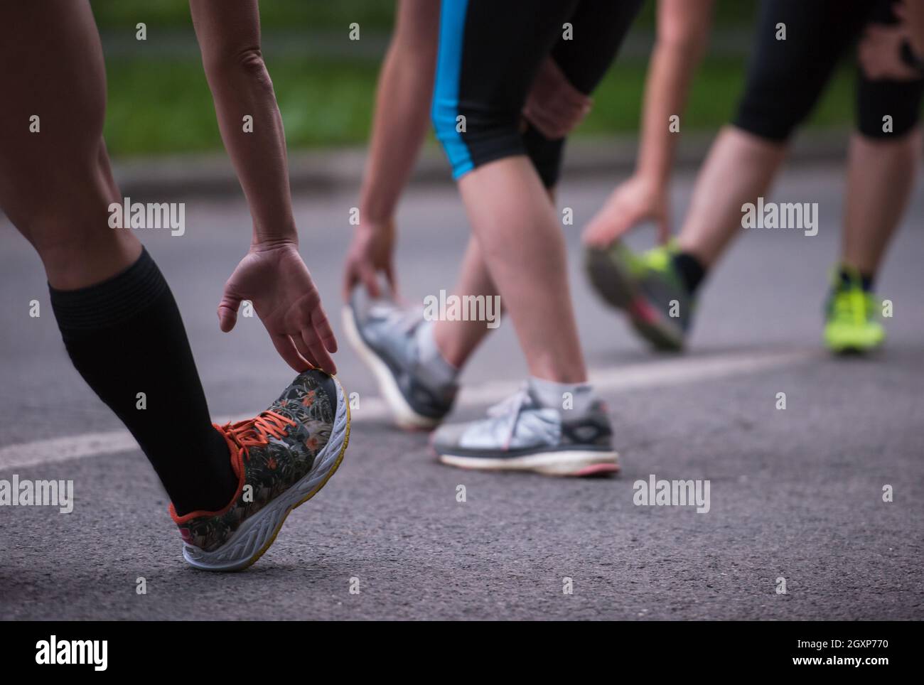 healthy runners team warming up and stretching in city park before ...