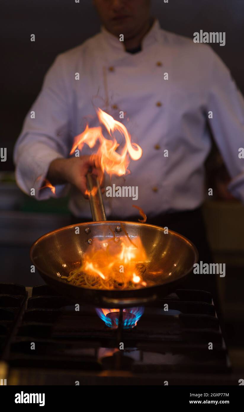 Chef cooking and doing flambe on food in restaurant kitchen Stock Photo ...
