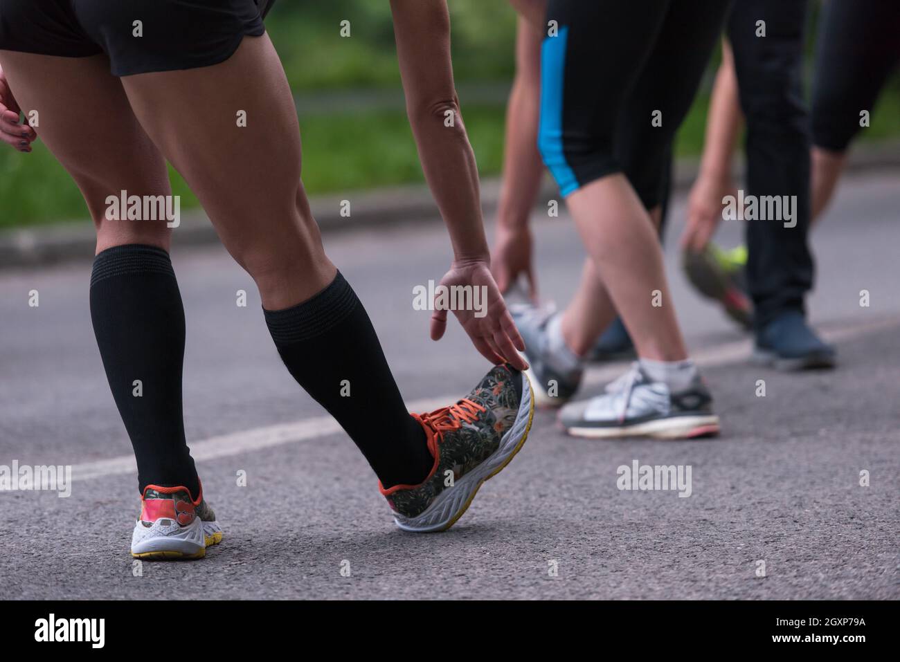 healthy runners team warming up and stretching in city park before ...