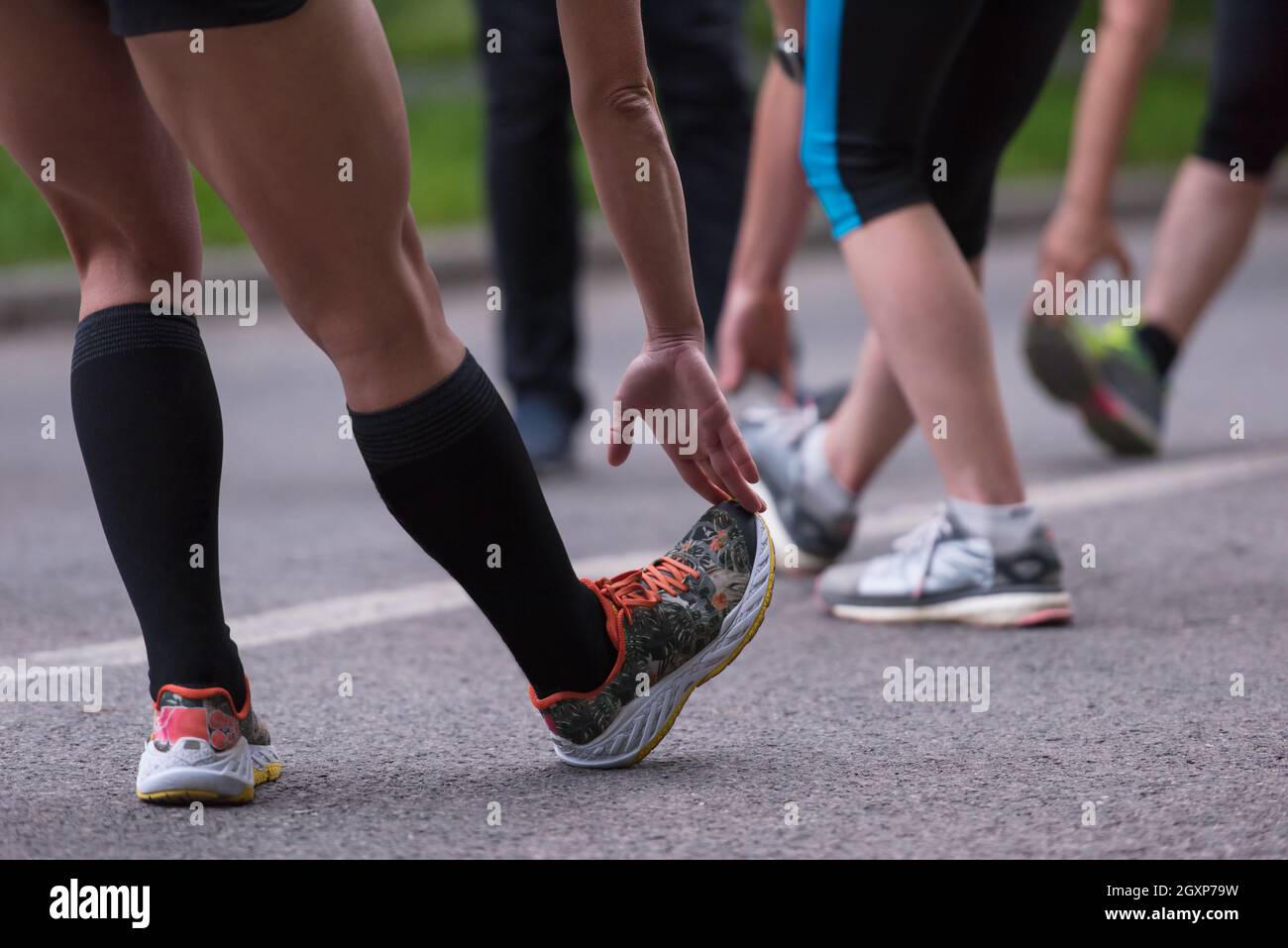 healthy runners team warming up and stretching in city park before ...