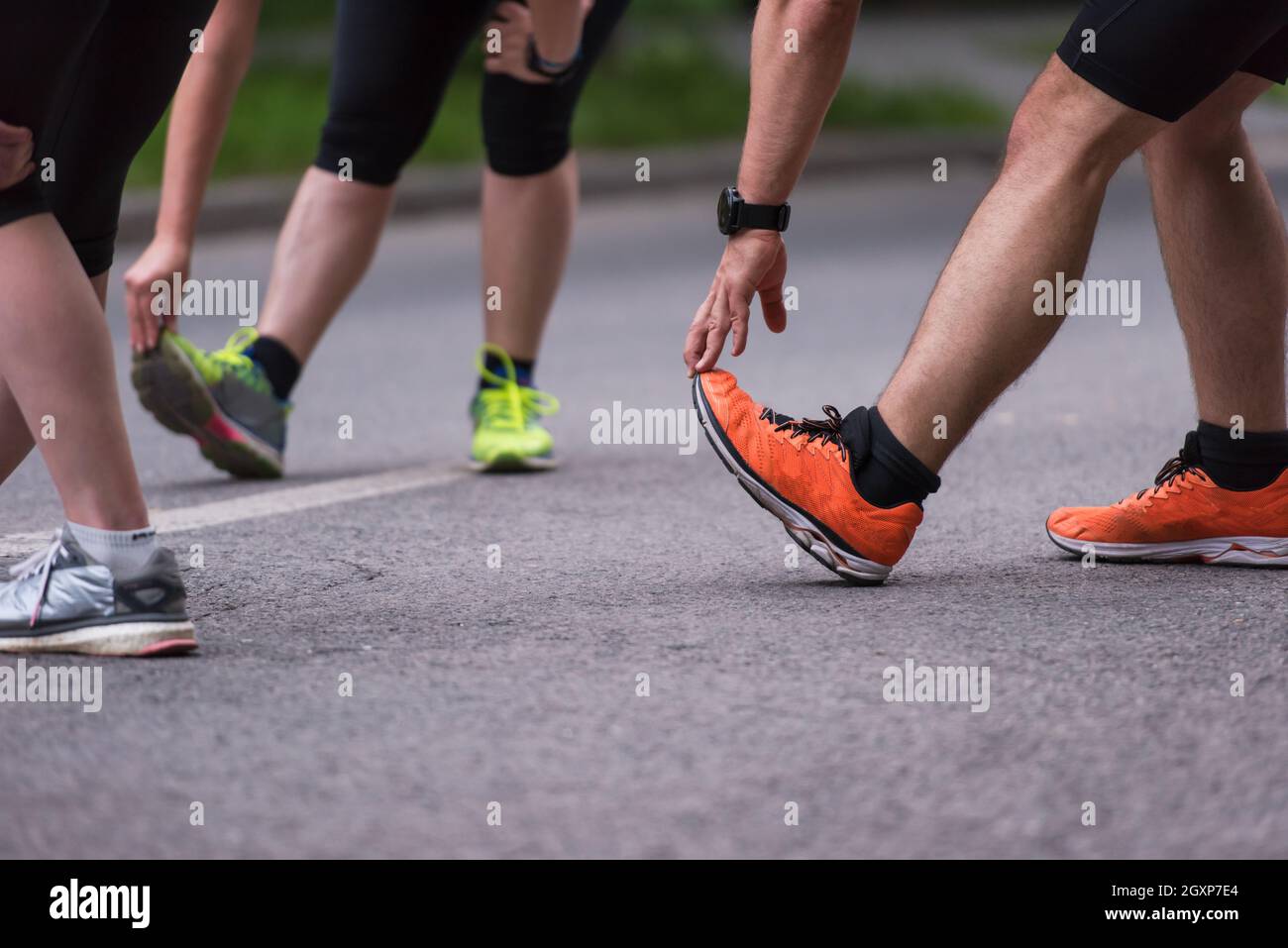 healthy runners team warming up and stretching in city park before ...