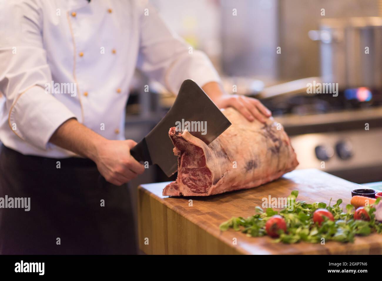 chef using ax while cutting big piece of beef on wooden board in ...