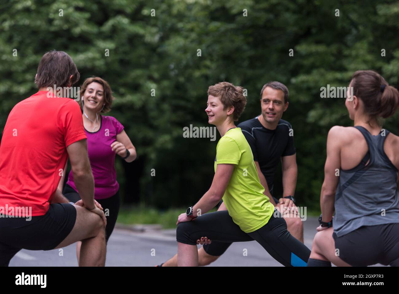 healthy runners team warming up and stretching in city park before ...