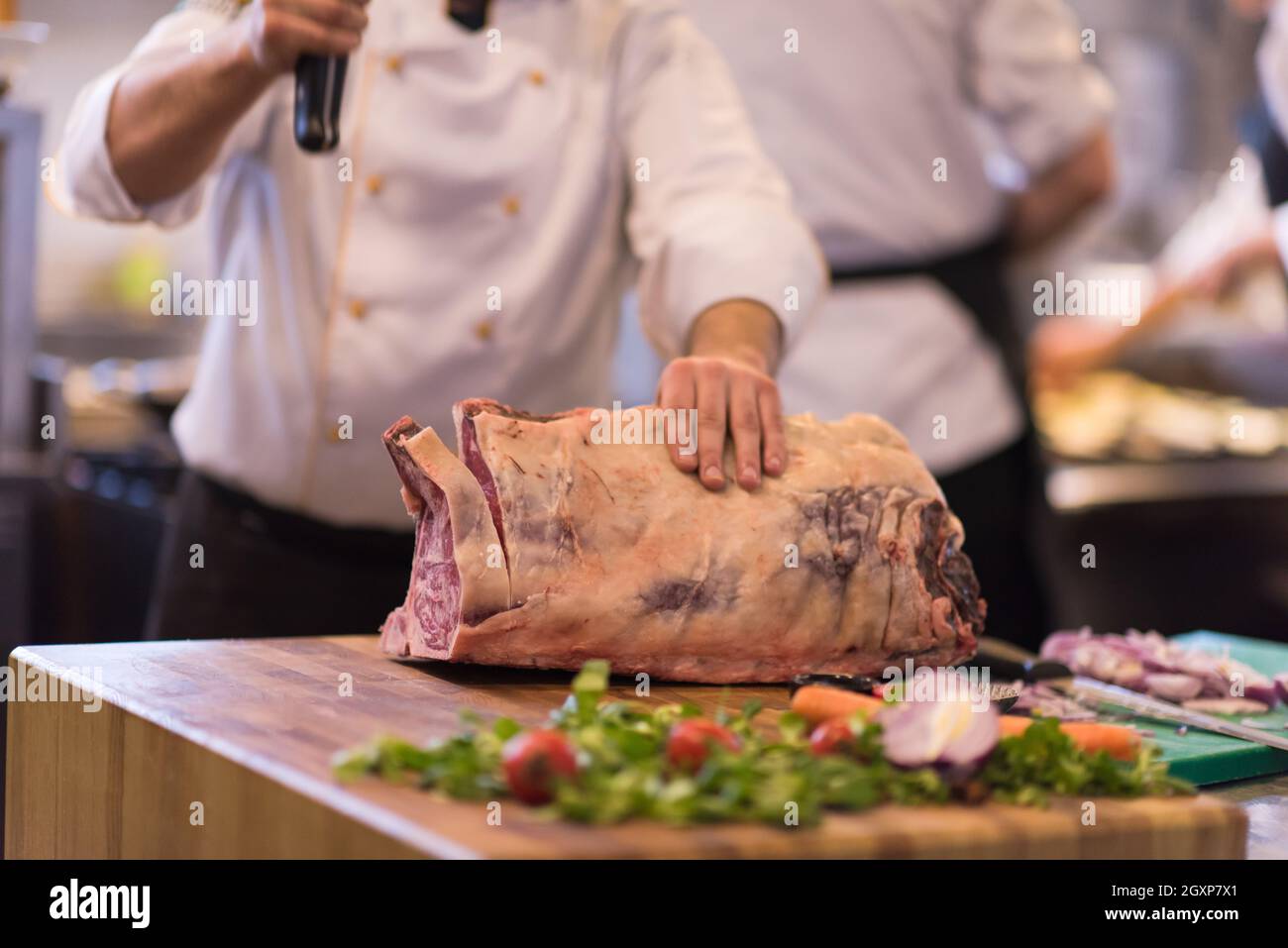 chef using ax while cutting big piece of beef on wooden board in ...