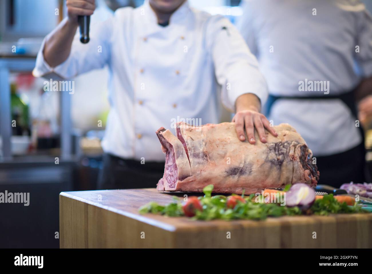 chef using ax while cutting big piece of beef on wooden board in ...