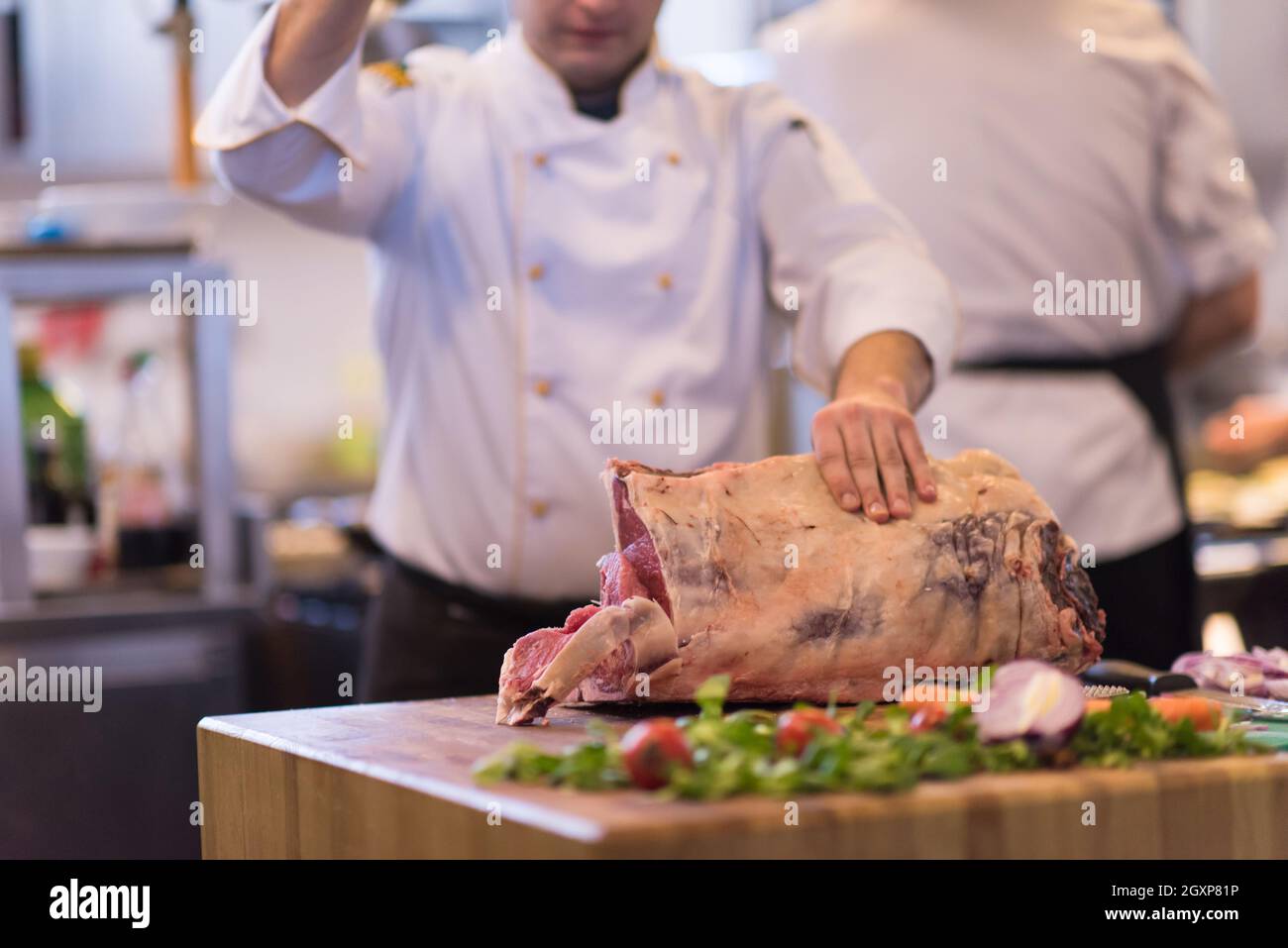 chef using ax while cutting big piece of beef on wooden board in ...