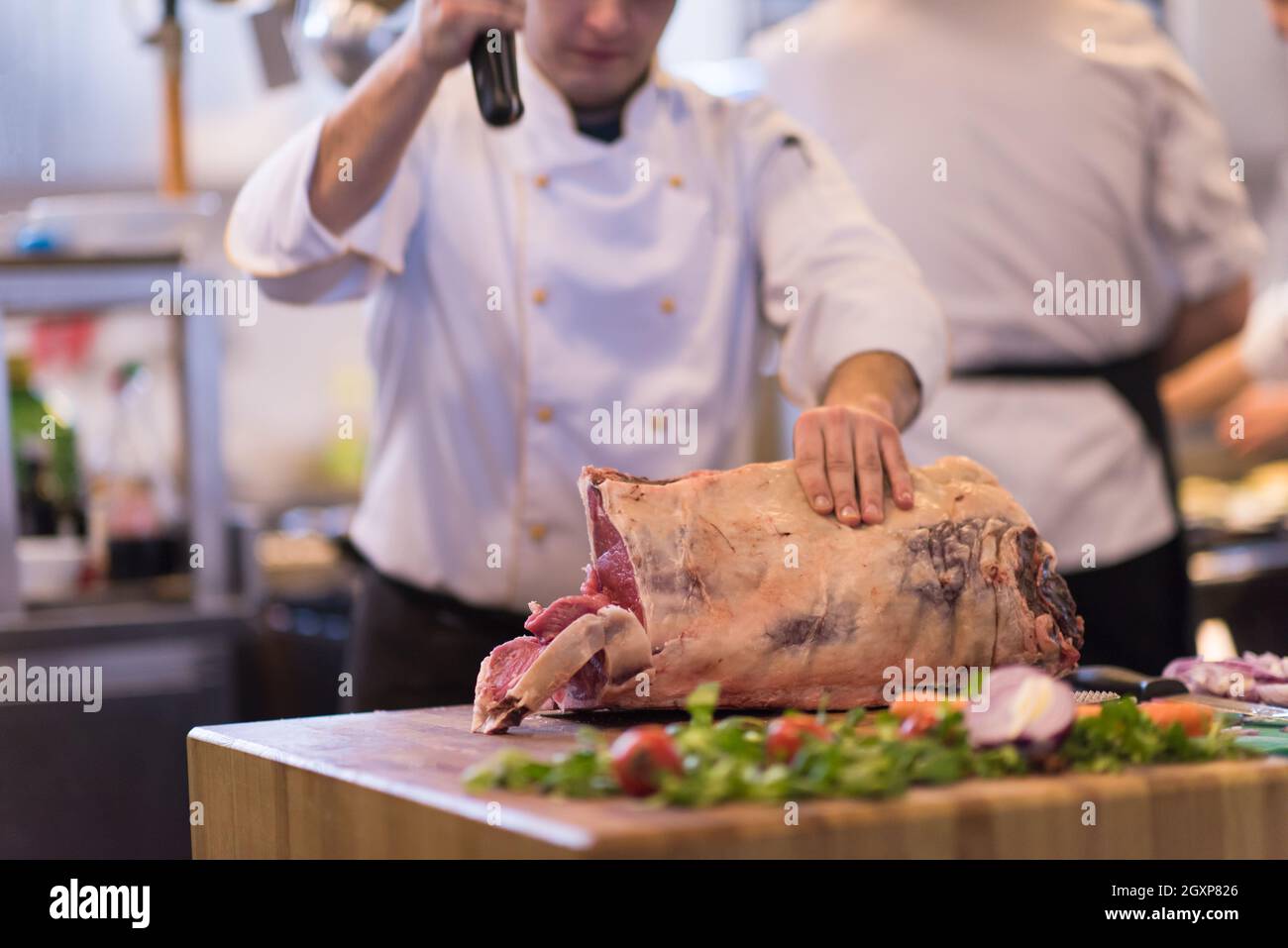 chef using ax while cutting big piece of beef on wooden board in ...