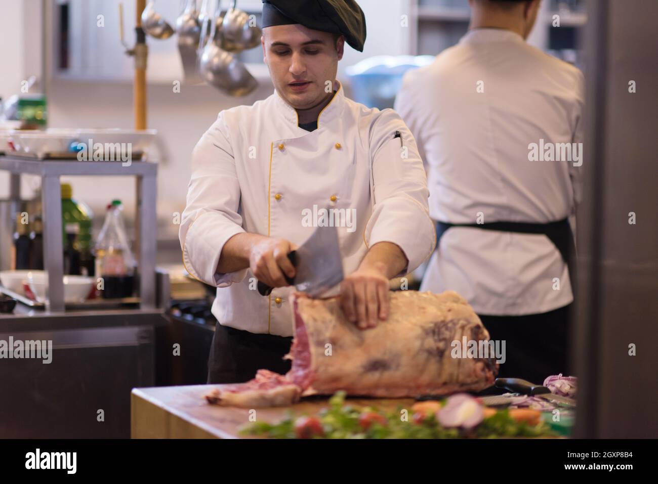 chef using ax while cutting big piece of beef on wooden board in ...