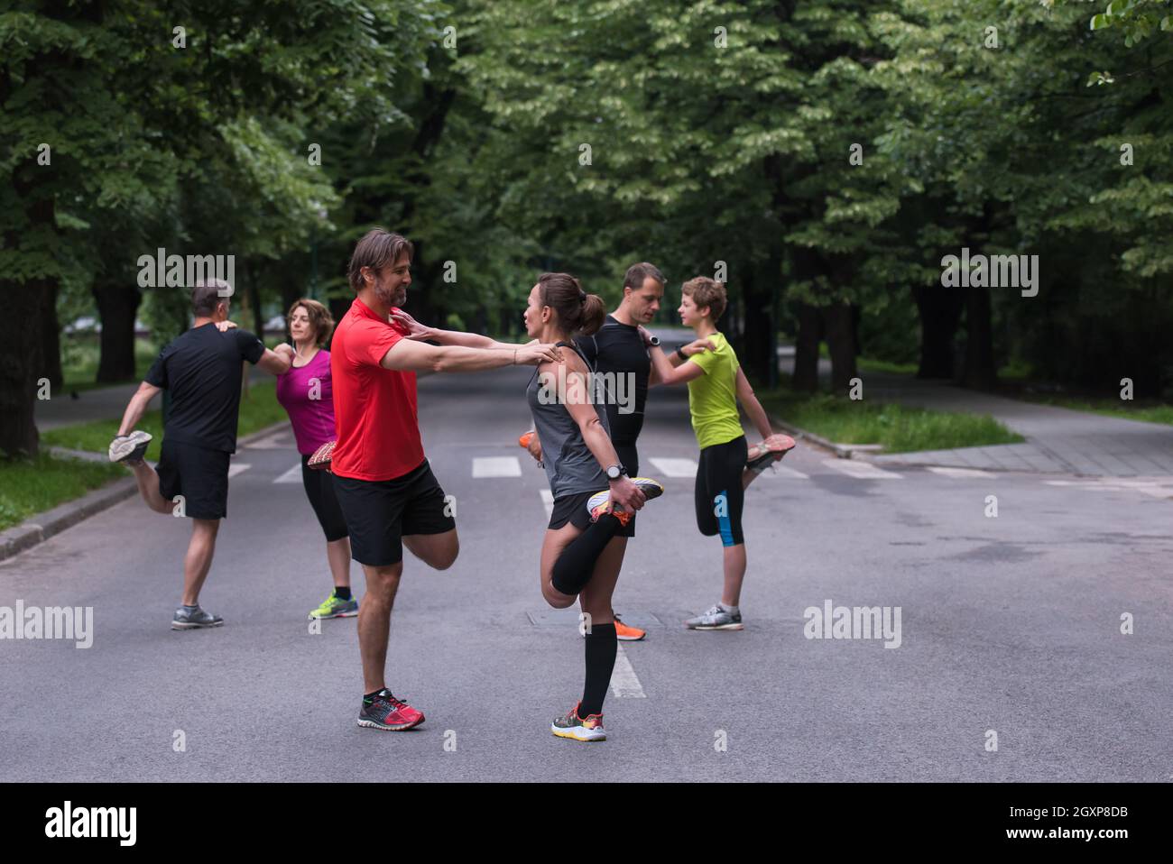 healthy runners team warming up and stretching in city park before ...