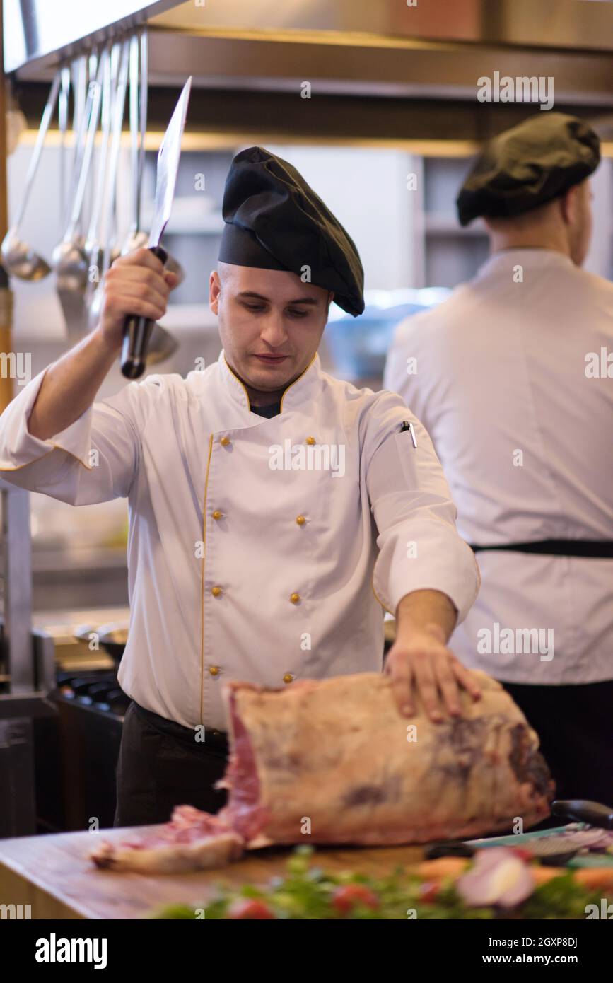 chef using ax while cutting big piece of beef on wooden board in ...