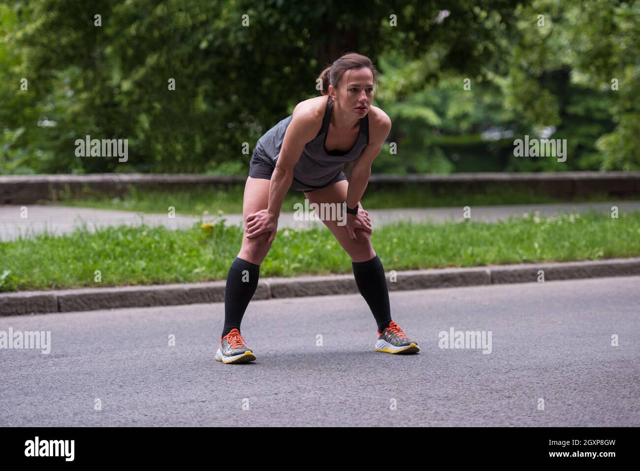 healthy female runner warming up and stretching in city park before ...