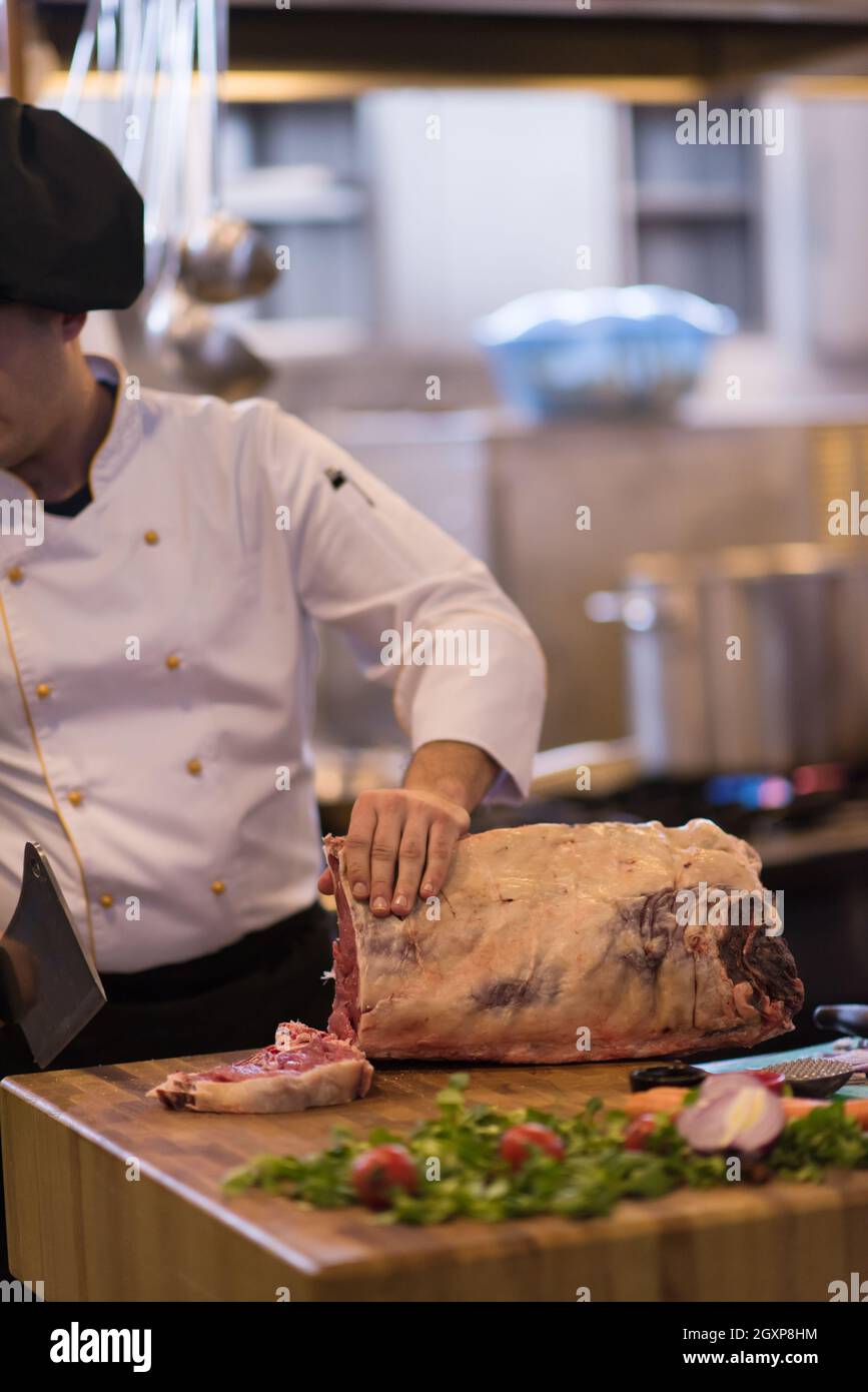 chef using ax while cutting big piece of beef on wooden board in ...