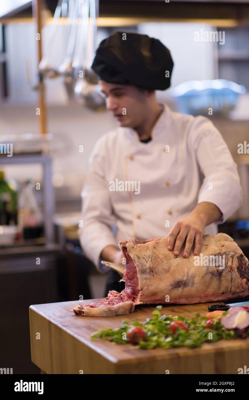 chef using ax while cutting big piece of beef on wooden board in ...