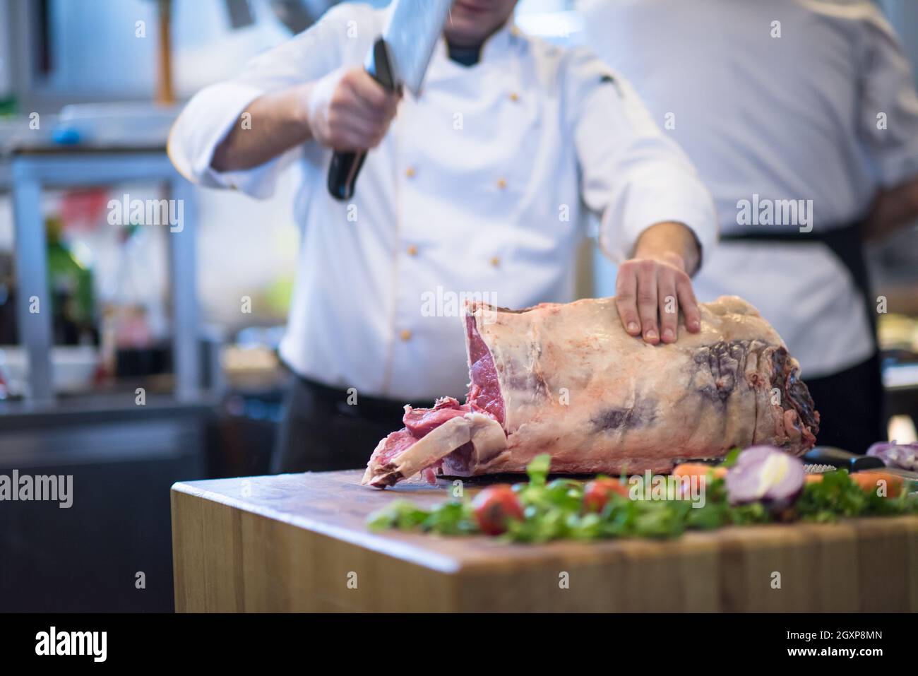 chef using ax while cutting big piece of beef on wooden board in ...